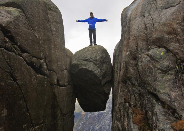 Kjeragbolten a rock balanced between two cliffs in Norway is a popular ...